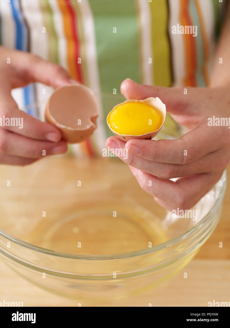 Girl's hands holding open egg shells with egg yolk in one side, above ...