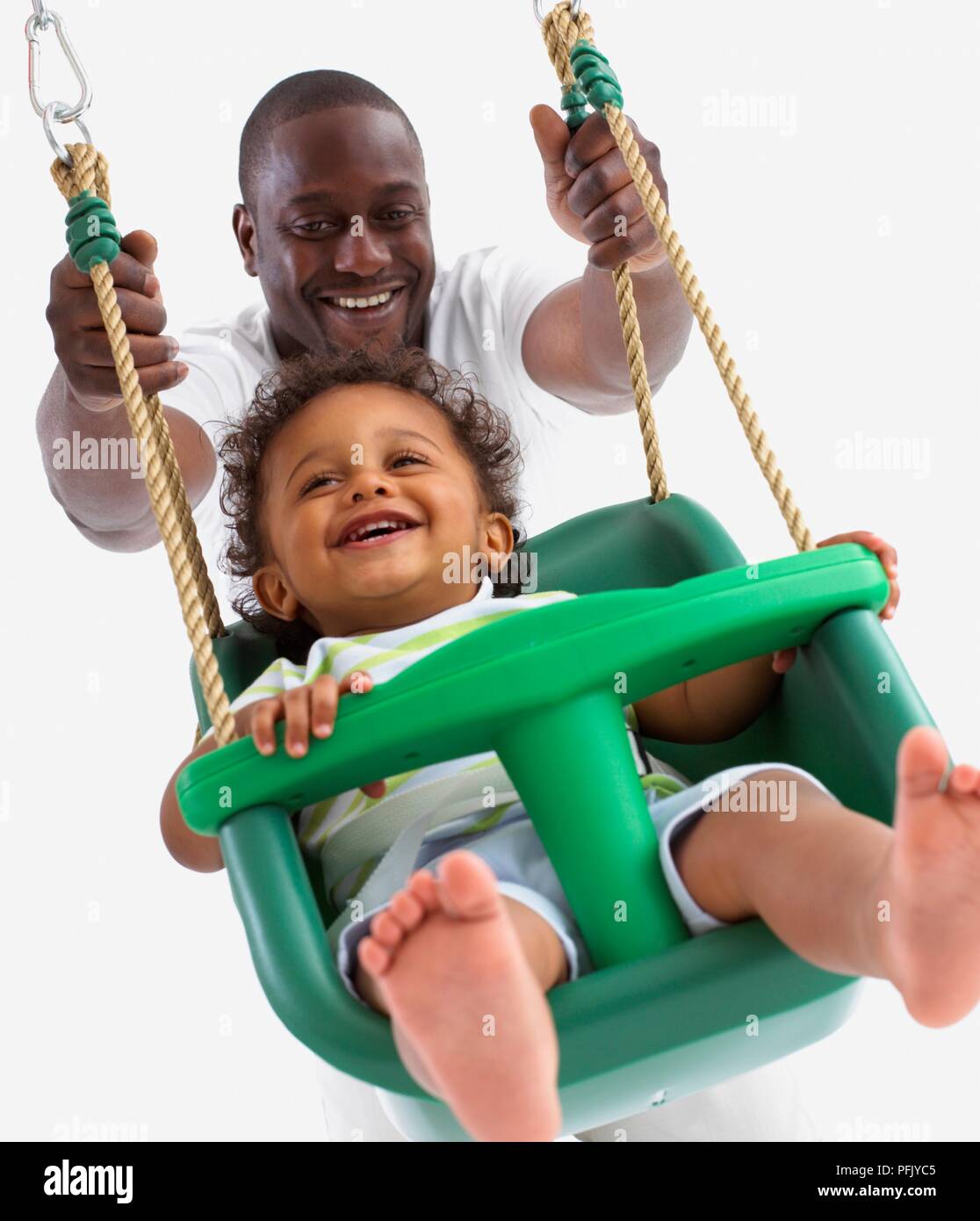Man pushing toddler boy on swing Stock Photo - Alamy