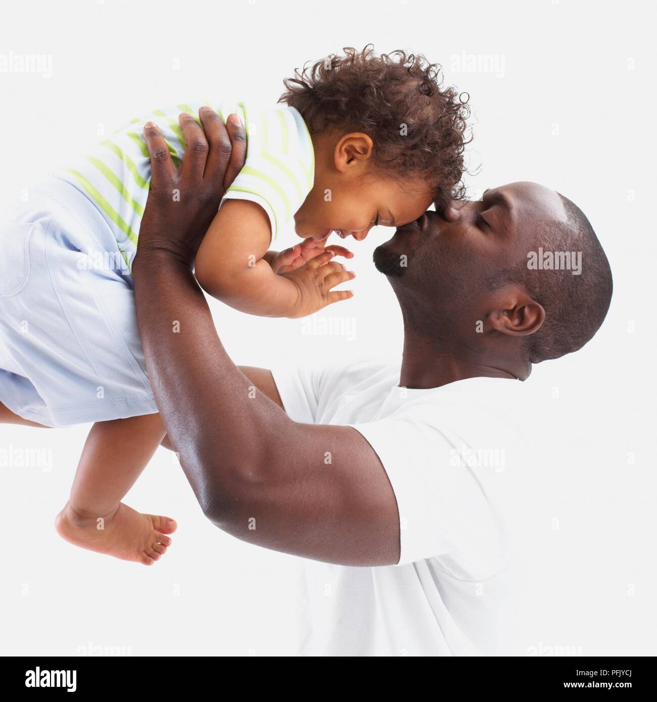 Man lifting toddler boy, kissing him on forehead, side view Stock Photo ...