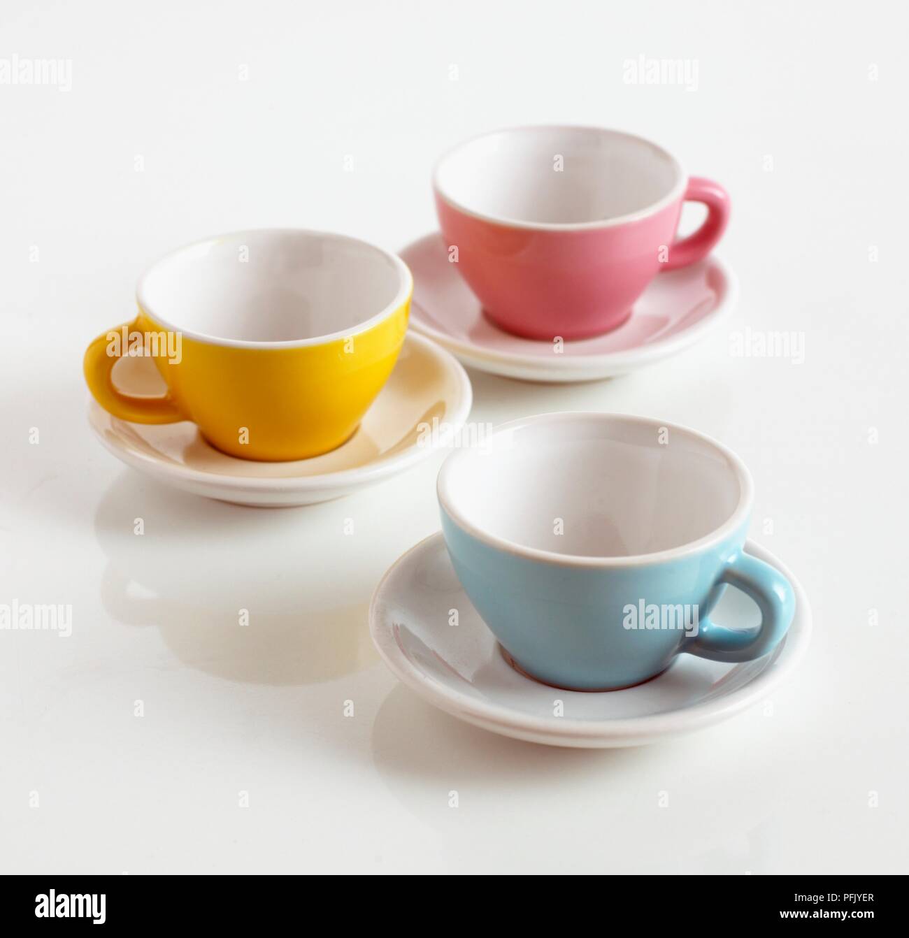 Pink, yellow and blue cups on saucers Stock Photo - Alamy