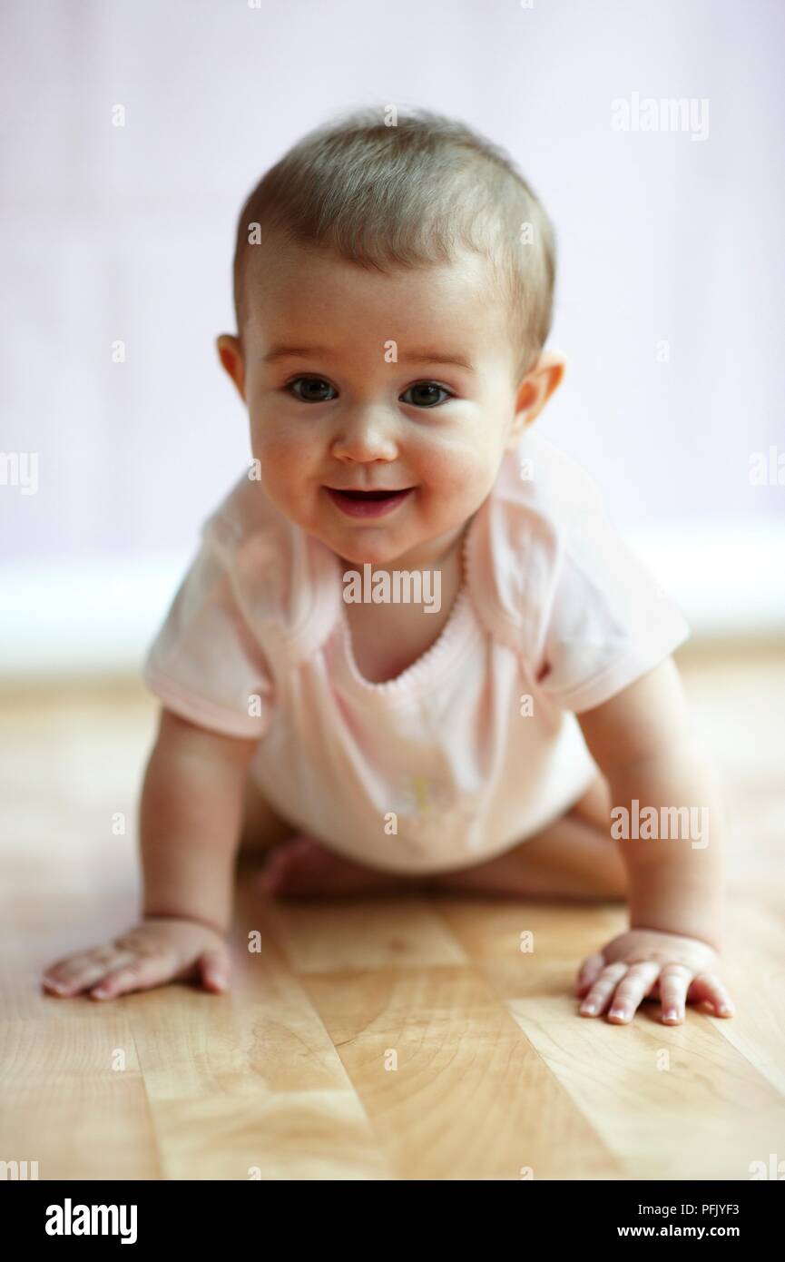 Baby girl crouching on floor, front view Stock Photo - Alamy