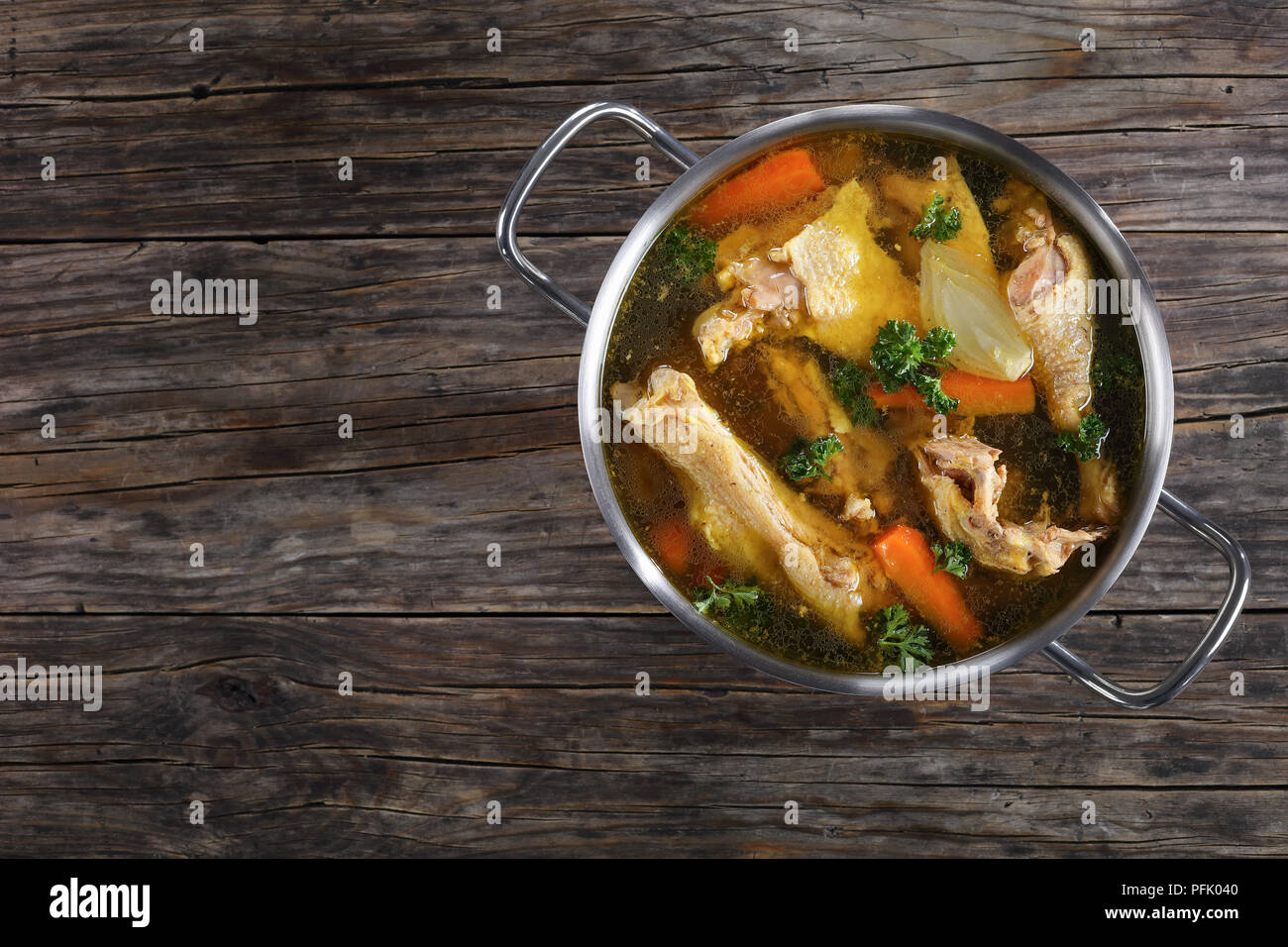 clear Chicken broth with pieces of rooster meat on bone and vegetables ...