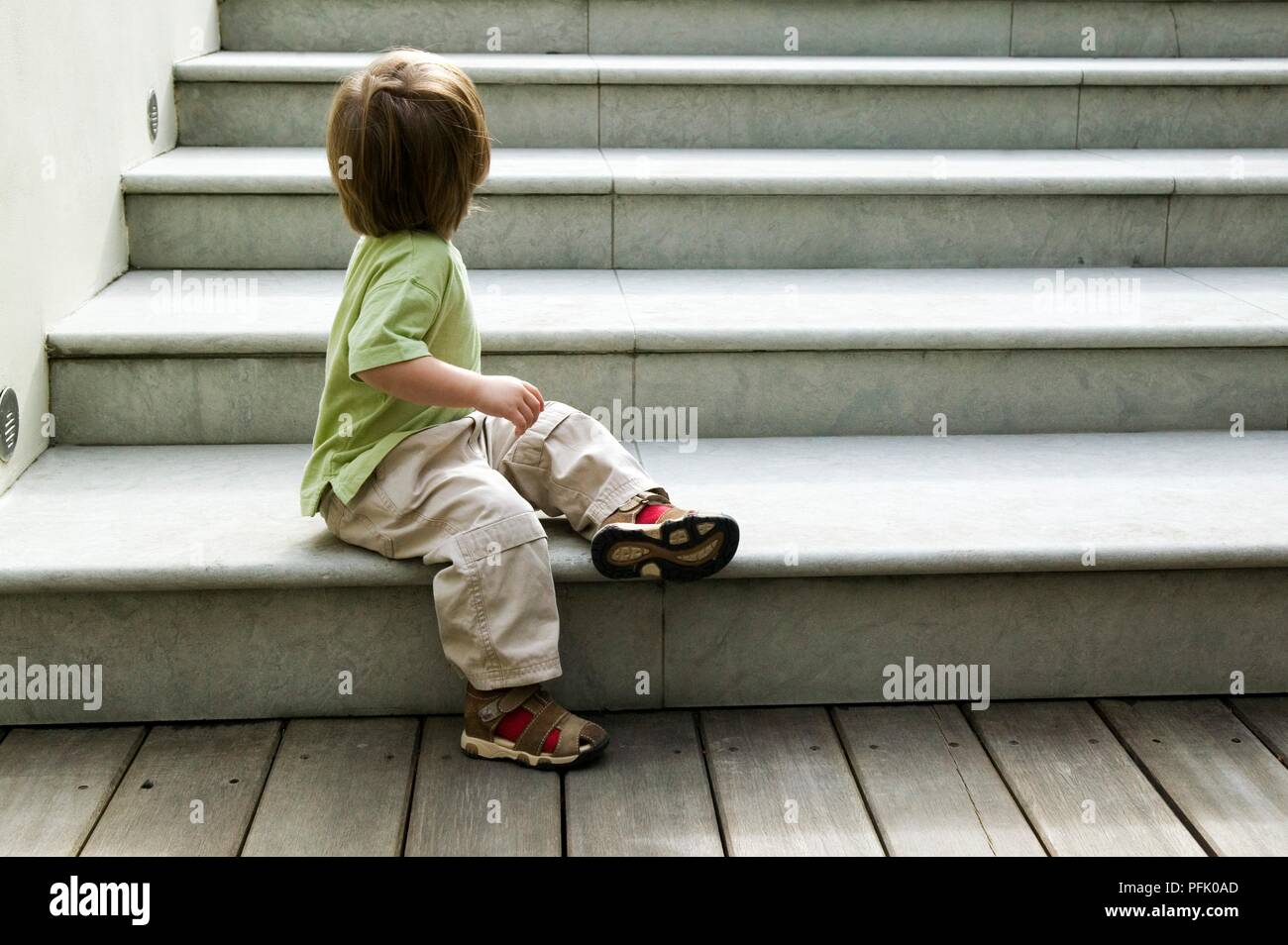 Toddler sitting at the bottom of set of steps, looking up Stock Photo ...