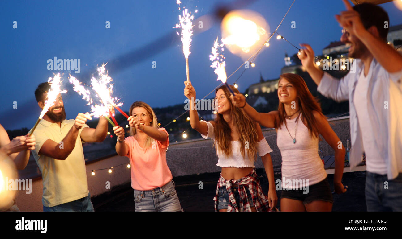 Friends enjoying a rooftop party and dancing with sparklers Stock Photo ...