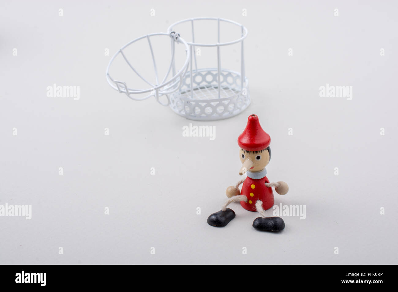 Metal cage and Little puppet pinocchio made of wood Stock Photo - Alamy