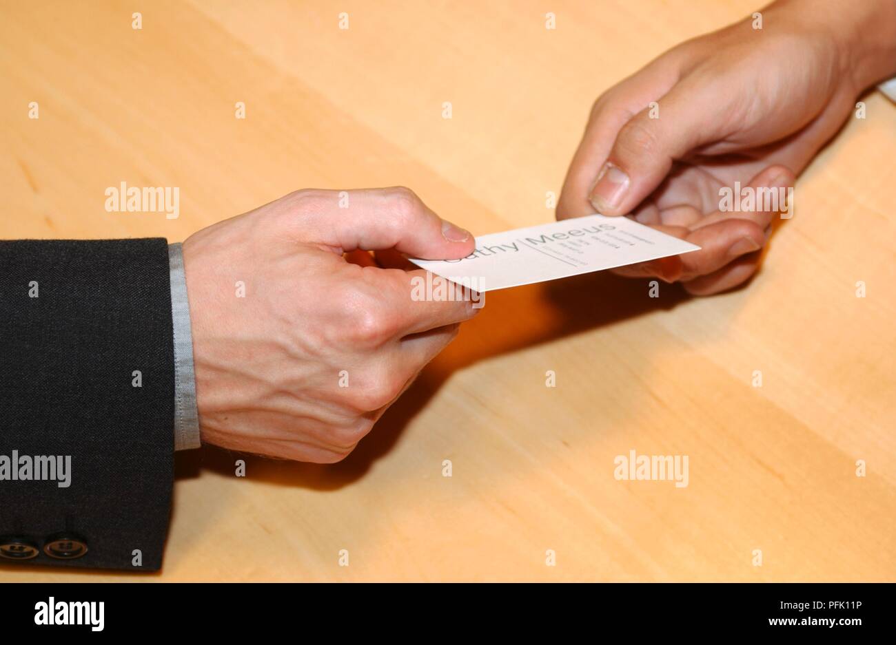 Two men exchanging business card across desk Stock Photo - Alamy
