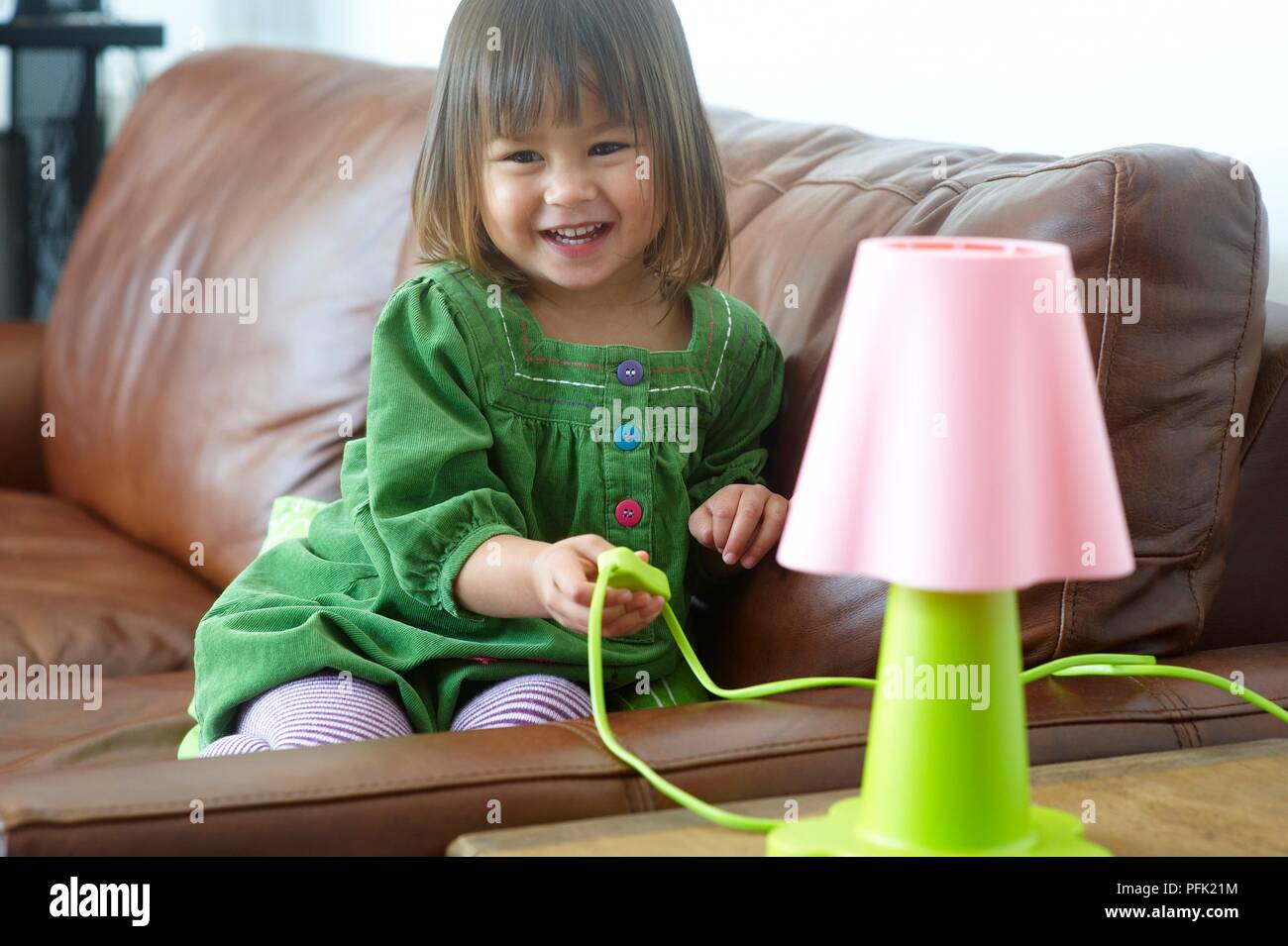Girl sitting on sofa holding light switch for table lamp Stock Photo ...