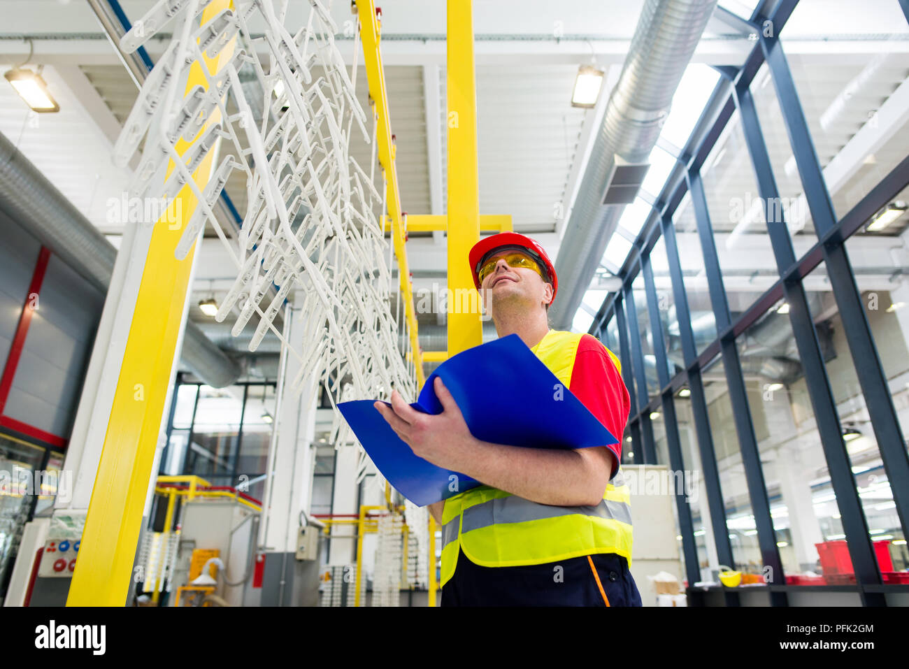 Factory supervisor checking production line holding blue folder with ...