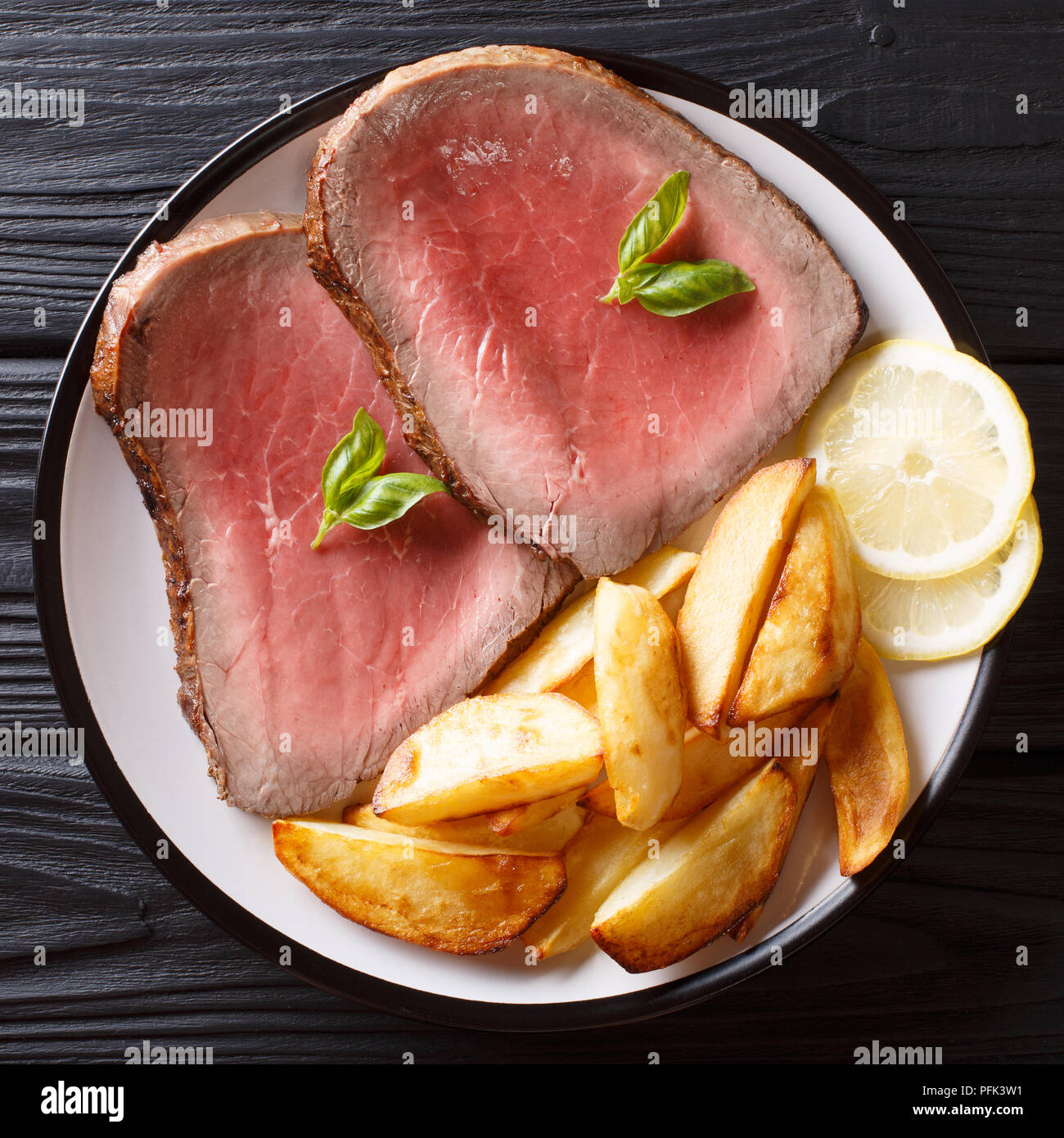 Beef steak is served with roasted potatoes and lemon close-up on a ...