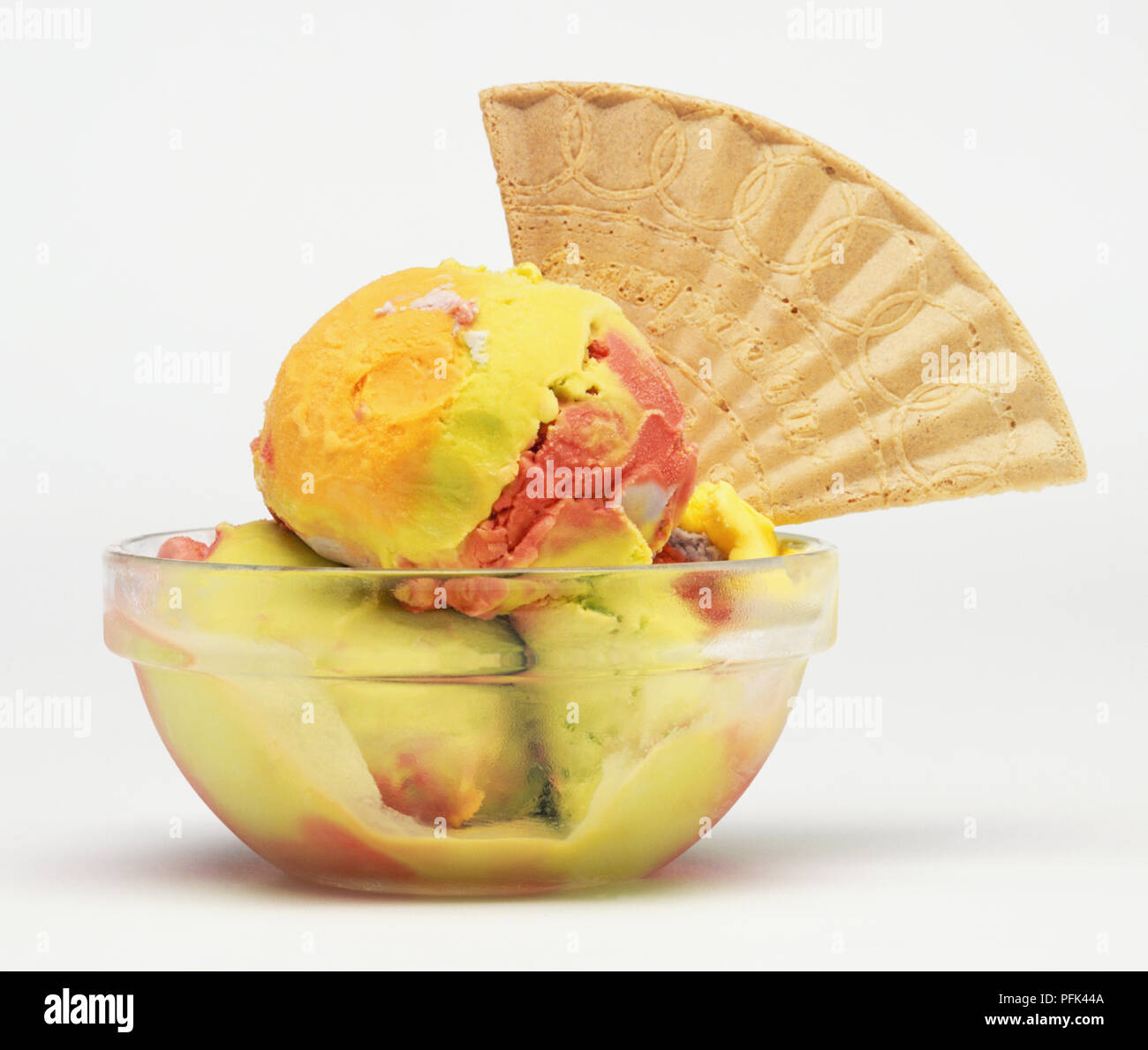 Multi-coloured, fruit-flavoured ice cream decorated with a wafer, in a ...