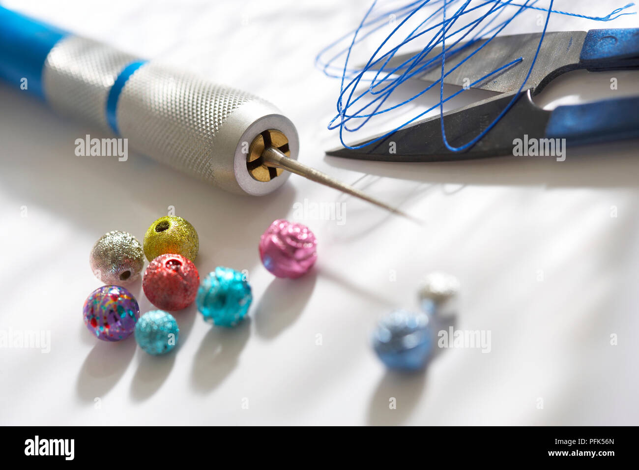 Reamer, coloured beads, blue wire and thread snip Stock Photo - Alamy