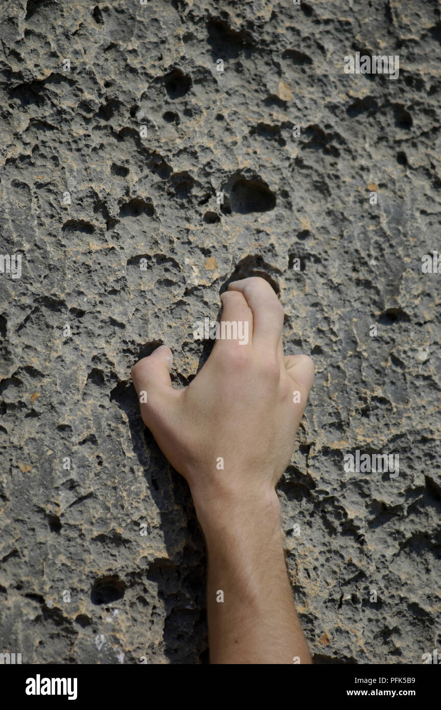 Hand clinging onto rock face Stock Photo - Alamy