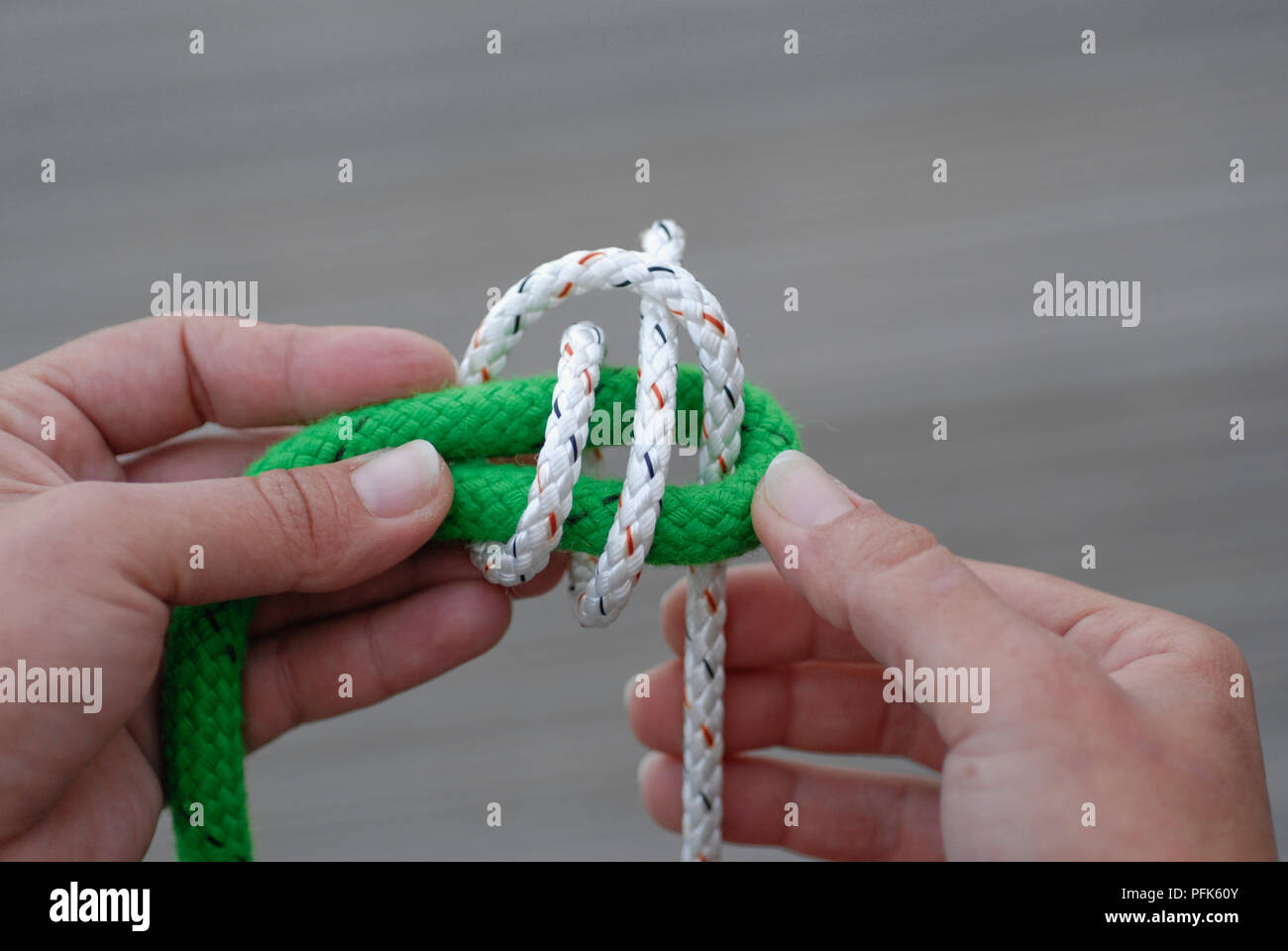 Hands tying knot around rope Stock Photo - Alamy