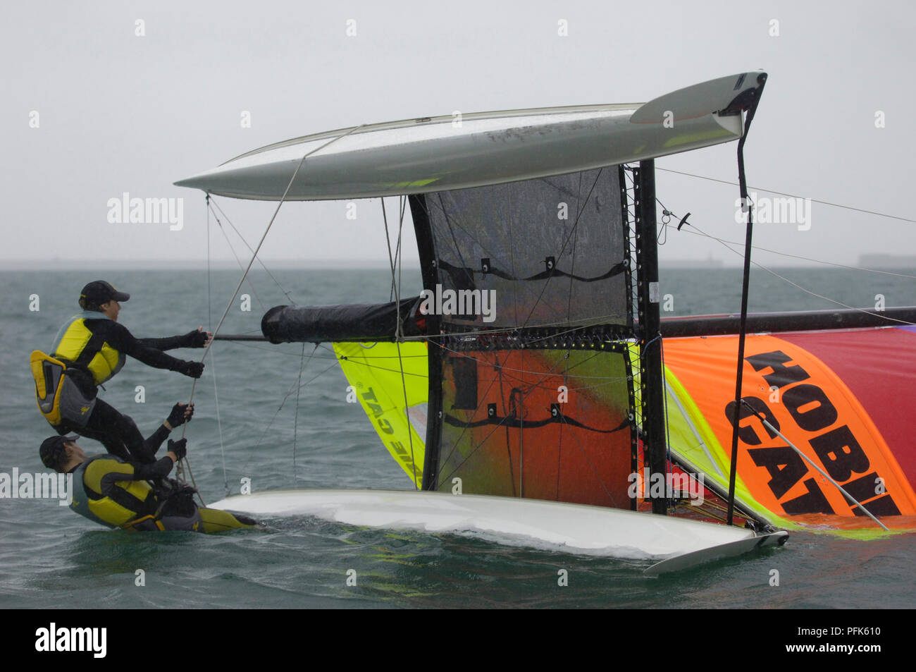 Man and woman at side of capsized catamaran, pulling at rope Stock ...