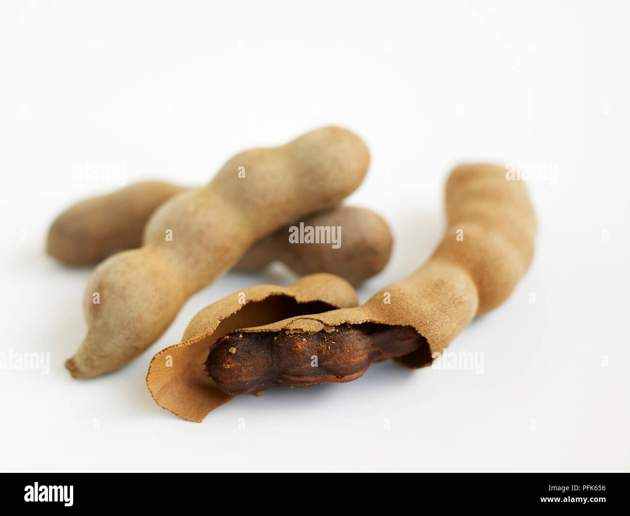 Three tamarind pods, one open showing seeds Stock Photo - Alamy