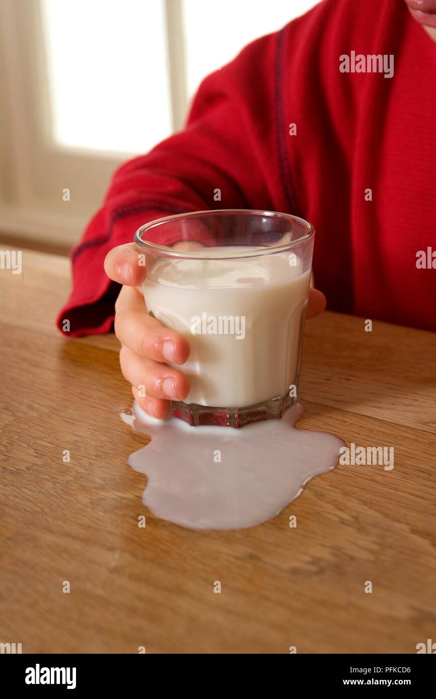 Boy's hand holding glass of spilt milk Stock Photo - Alamy