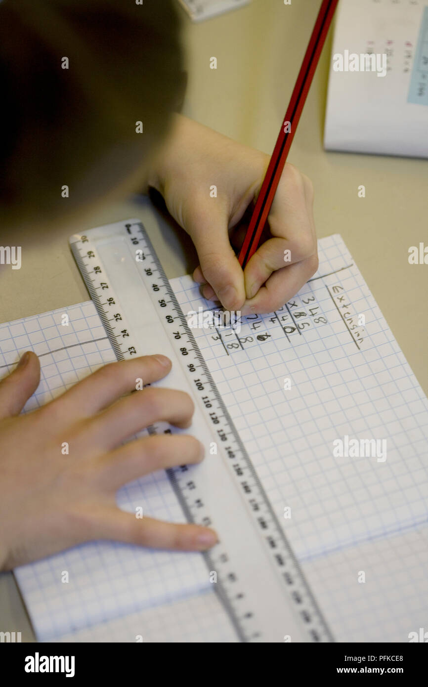 Girl doing calculation in exercise book, using pencil and ruler, close ...
