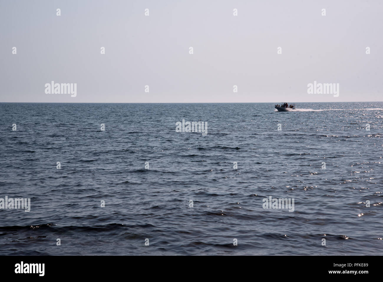 Small boat riding at distance in blue water of sea in summertime Stock ...
