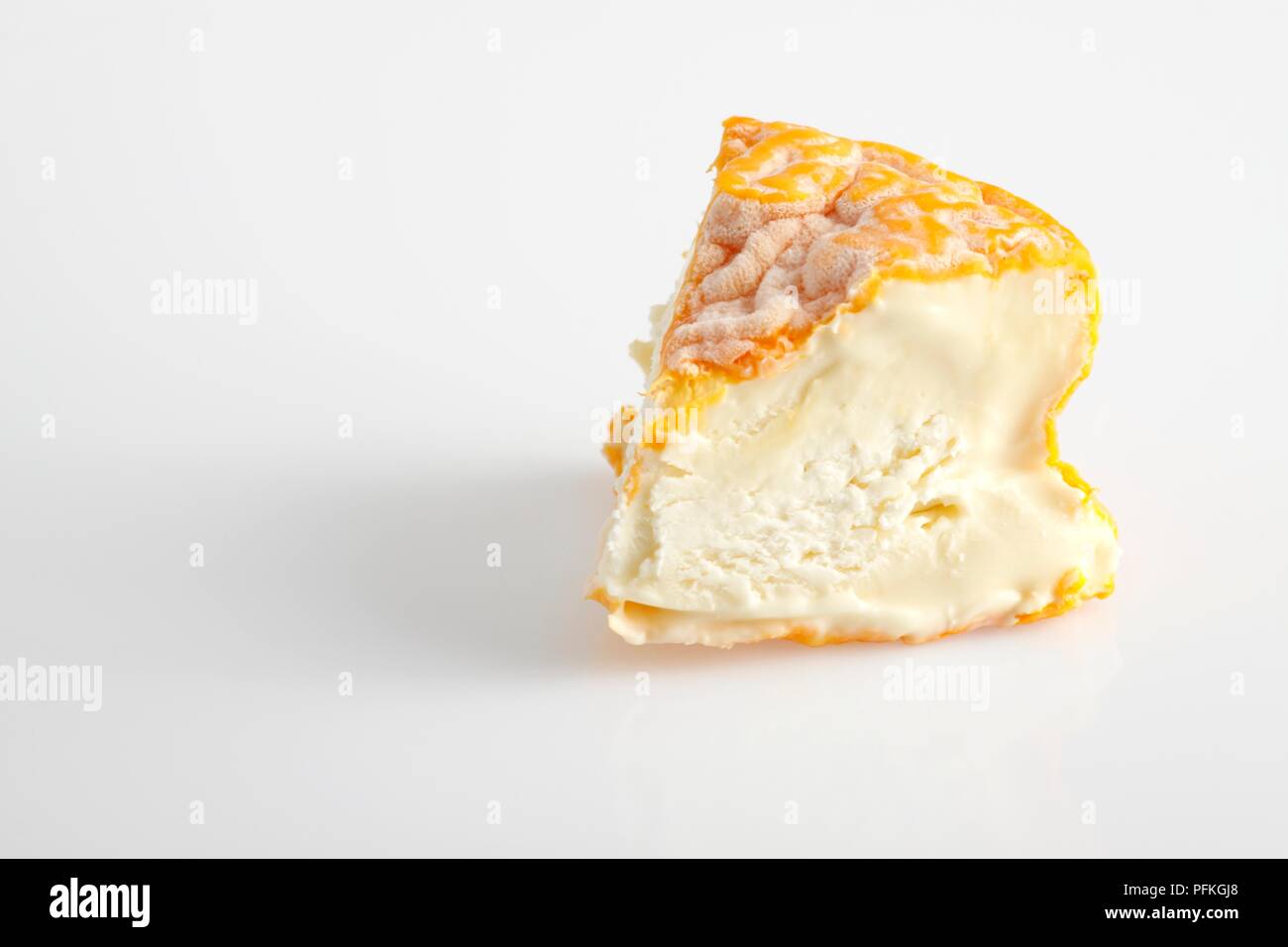 Slice of French Langres AOC cow's milk cheese showing orange rind Stock ...