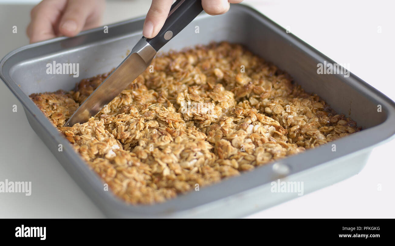 Using small kitchen knife to cut oatmeal flapjacks Stock Photo - Alamy
