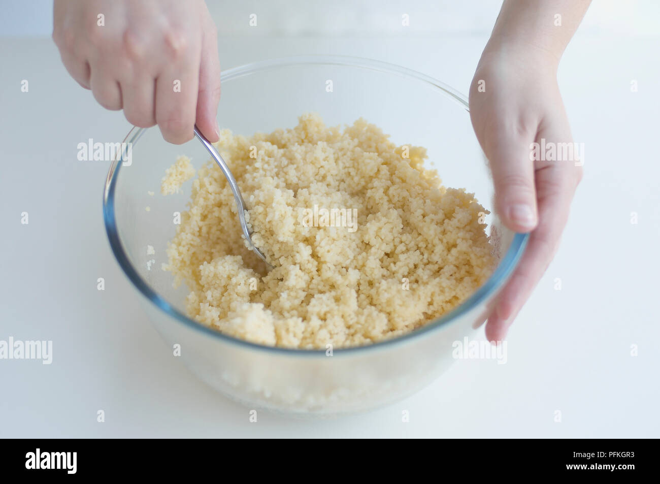 Using spoon to stir cous-cous in mixing bowl Stock Photo - Alamy