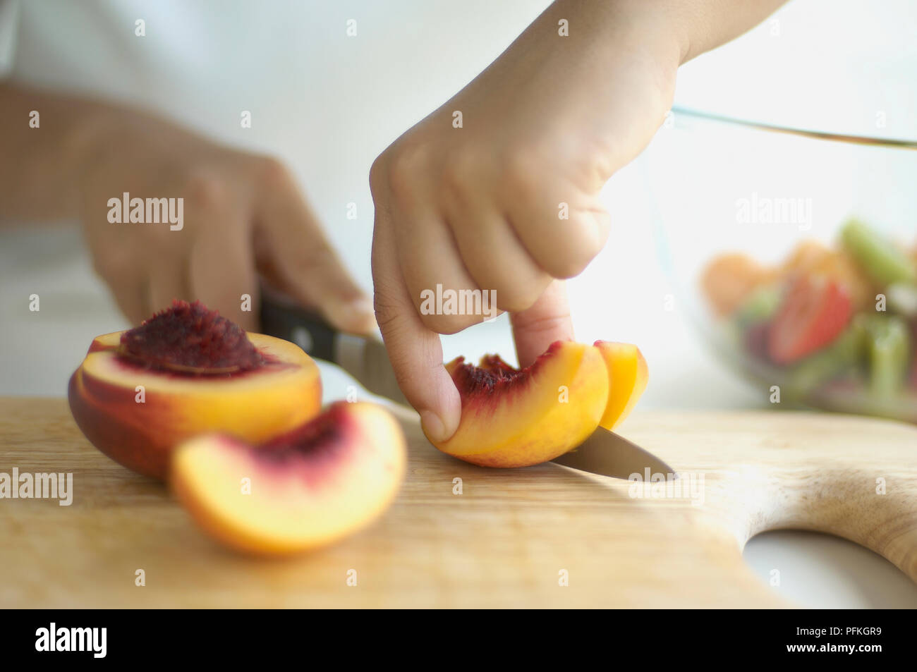 Child's hands slicing peach on chopping board, close-up Stock Photo - Alamy