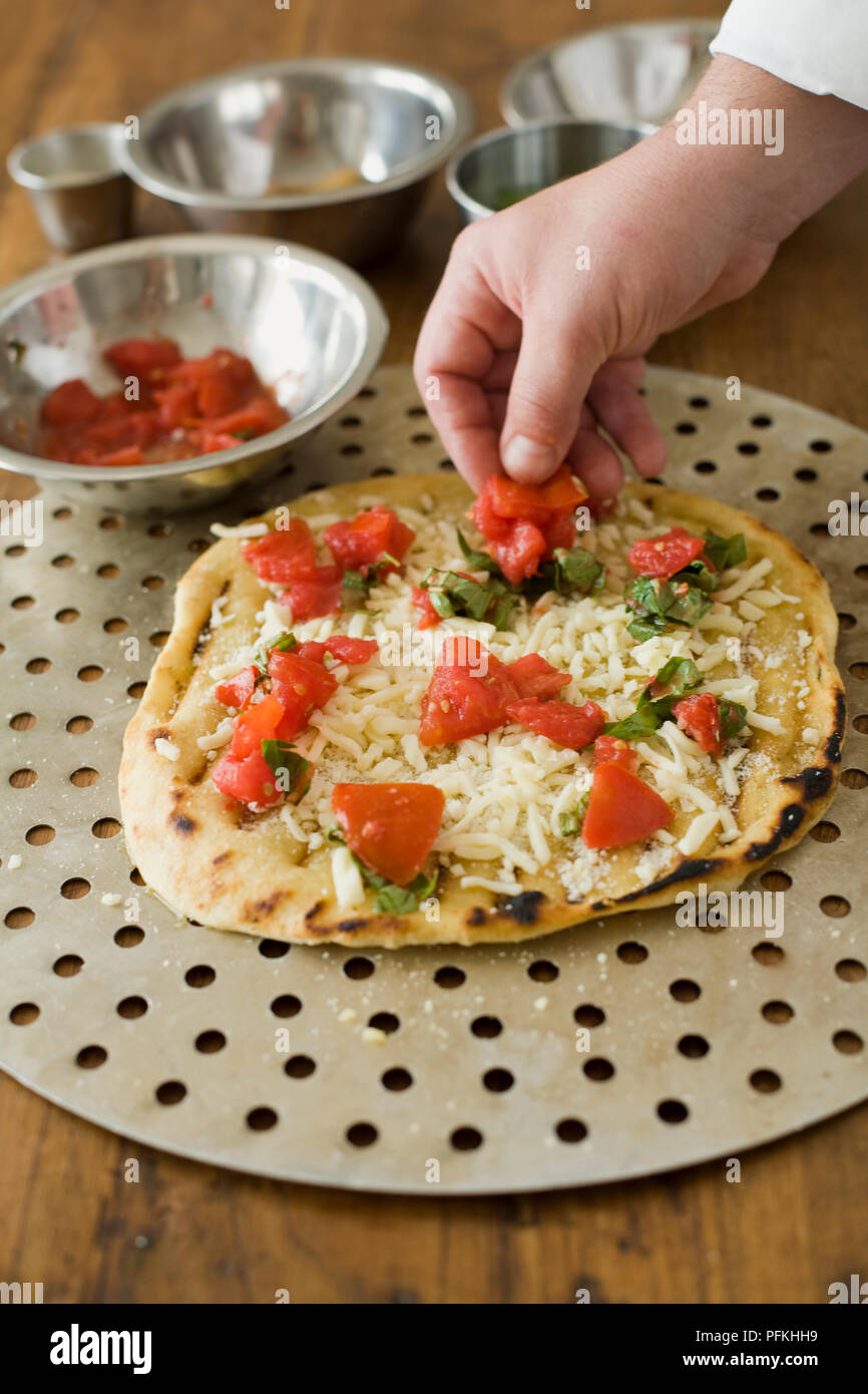 Hand adding toppings onto pizza, close-up Stock Photo - Alamy