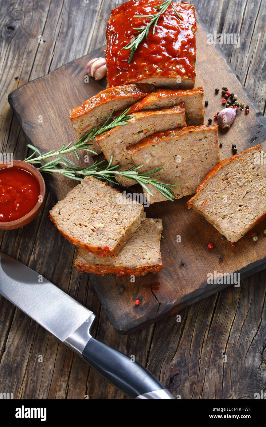 delicious sliced meatloaf on wooden cutting board with garlic, rosemary ...