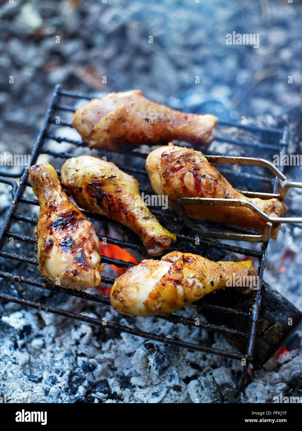 Grilling chicken legs above burning embers of camp fire Stock Photo - Alamy