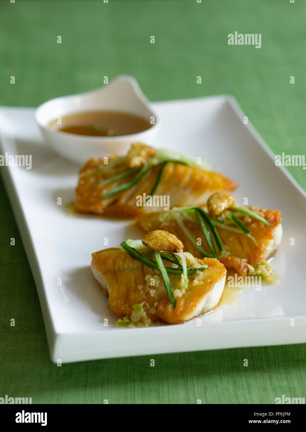 Pan-seared cod garnished with strips of cucumber, ginger and garlic ...