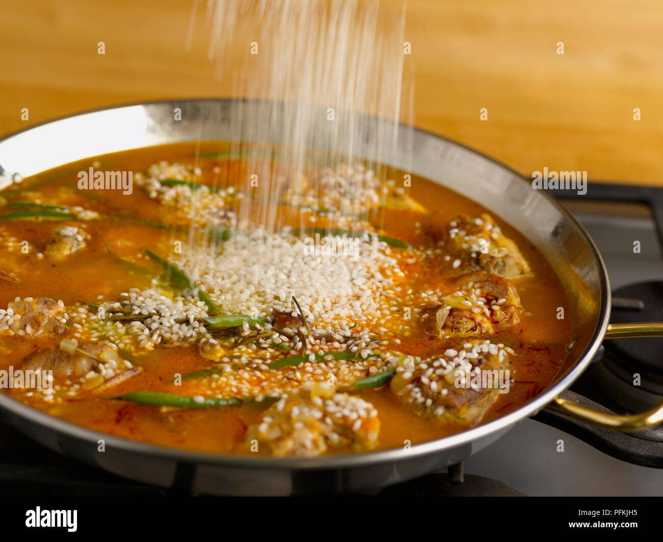 Adding rice to paella ingredients in pan, blurred motion Stock Photo ...