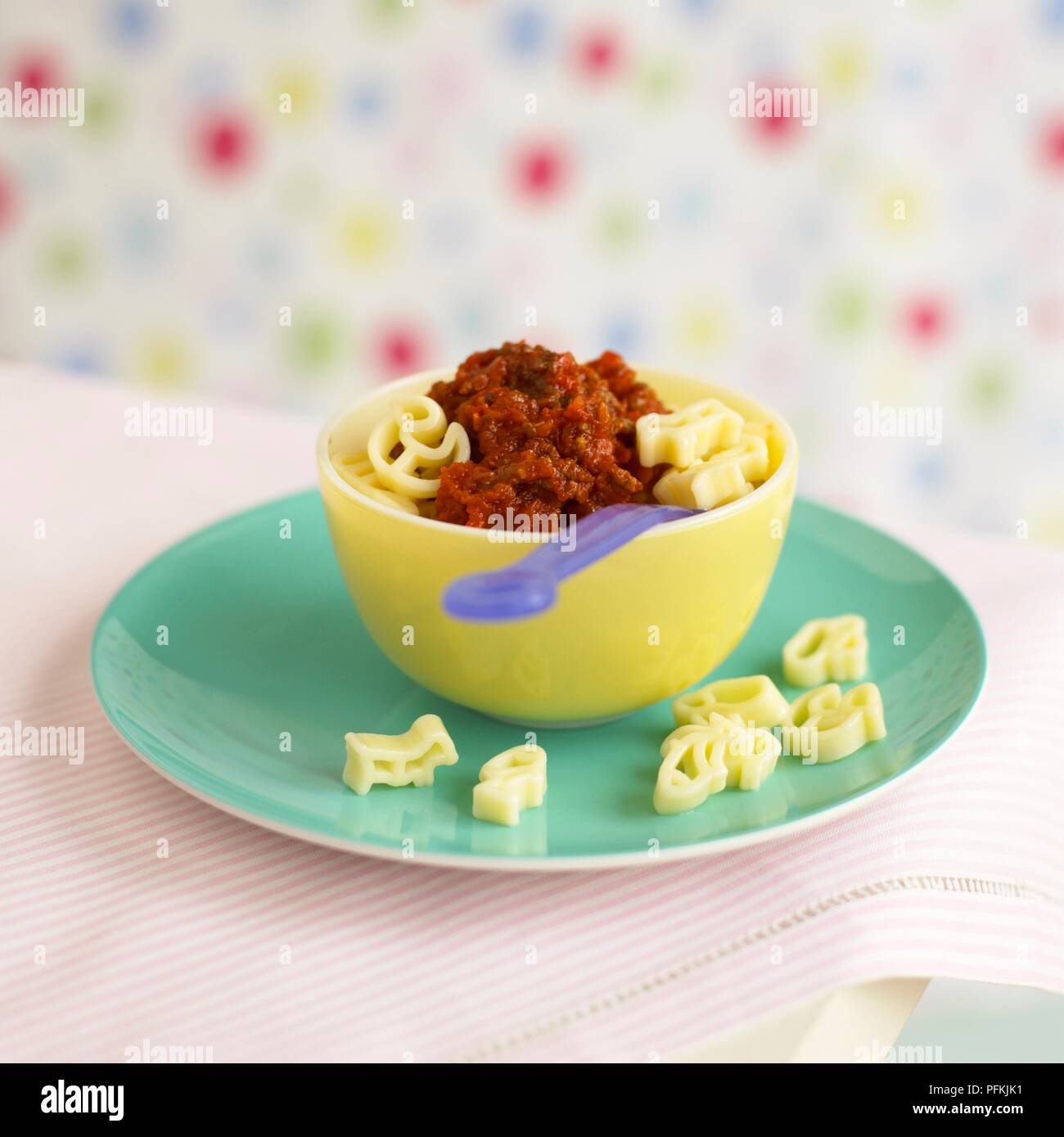 Animal shape pasta with Bolognese sauce in bowl, with plastic spoon, on ...
