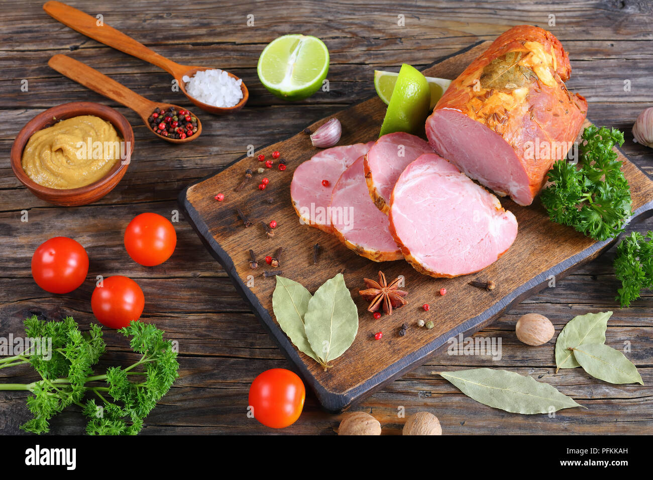 delicious ham cut in slices with spices, parsley and lime on dark ...