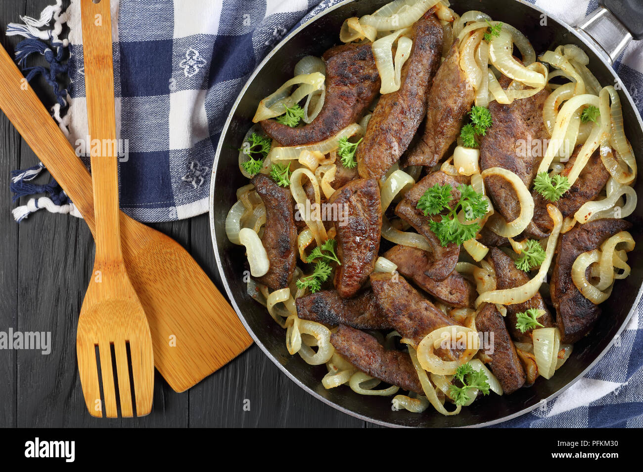 delicious fried veal liver pieces with onion rings in skillet on black ...