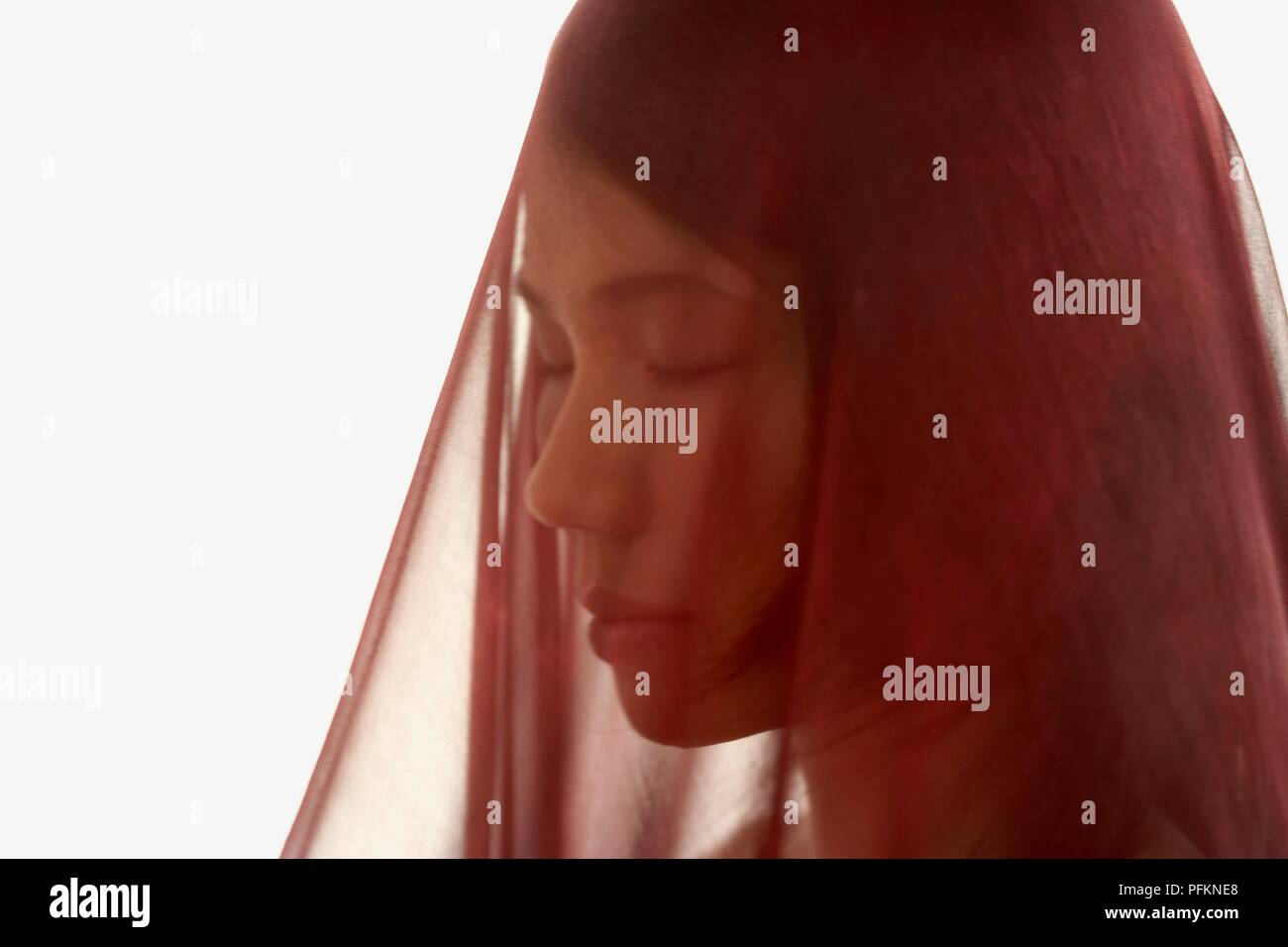 Headshot of a woman with a veil over her head and her eyes closed, side ...