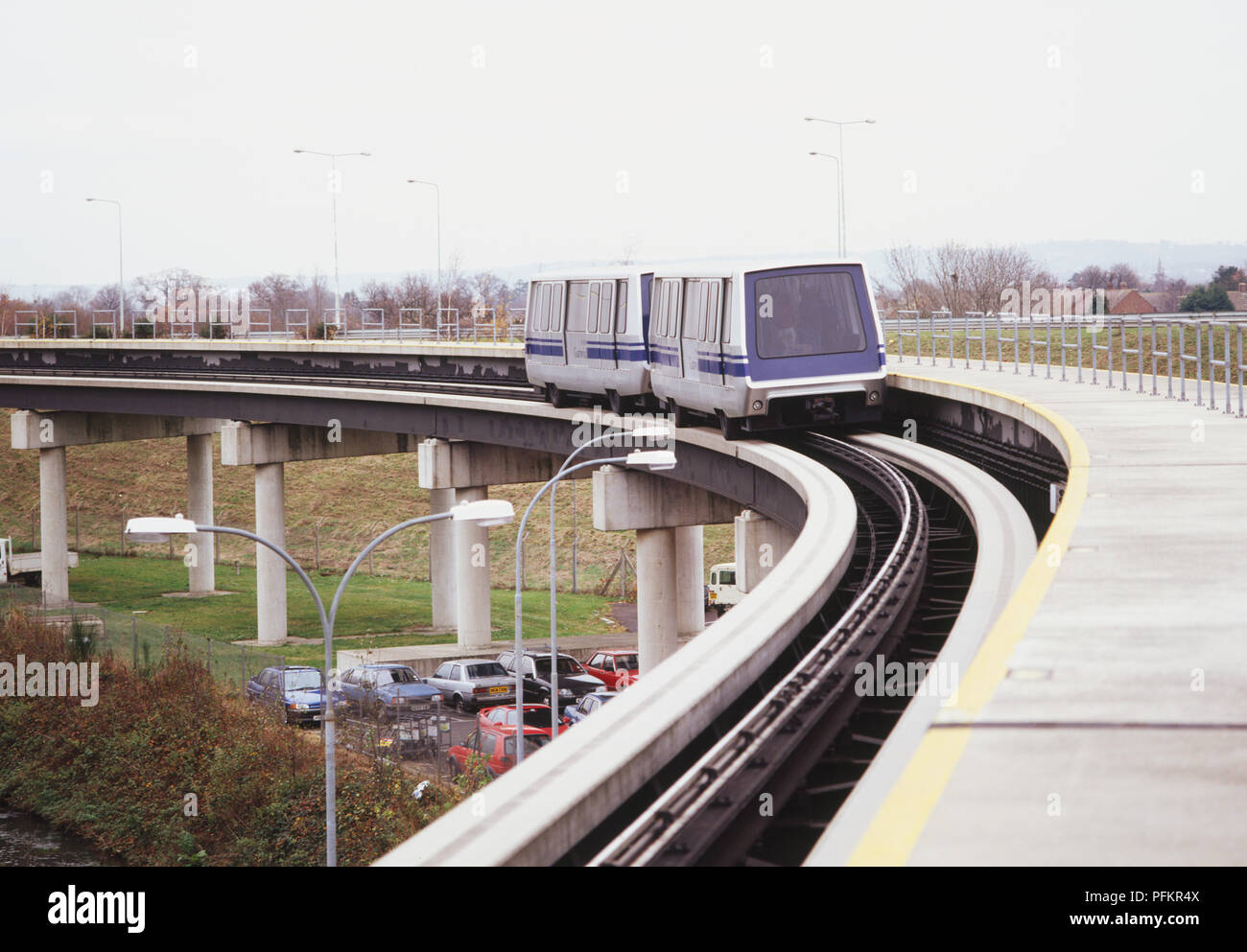 Airport transit train travelling along winding concrete tracks, side ...