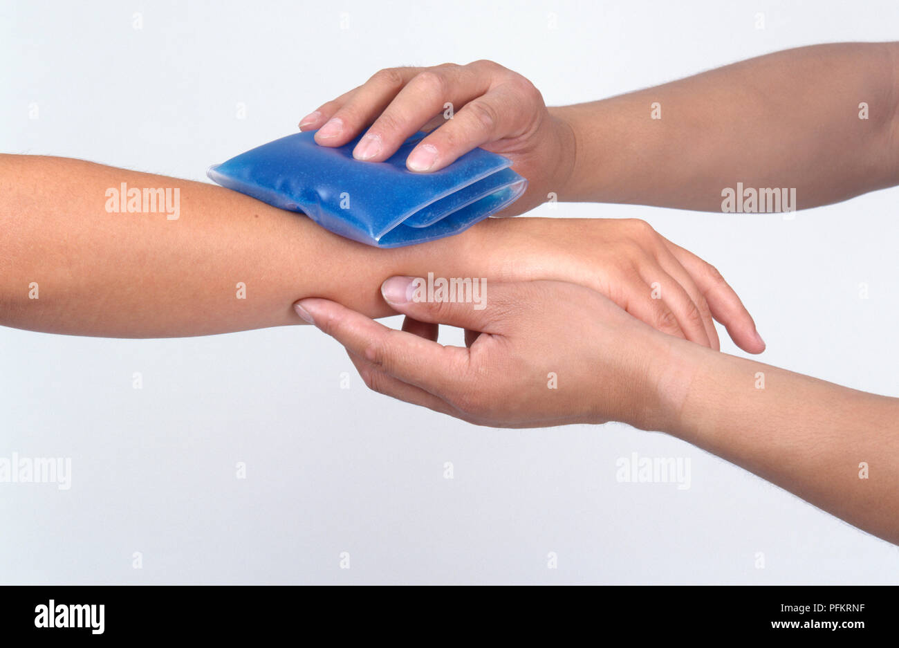 Woman's hand placing a cold pack on the arm of another woman, close-up ...
