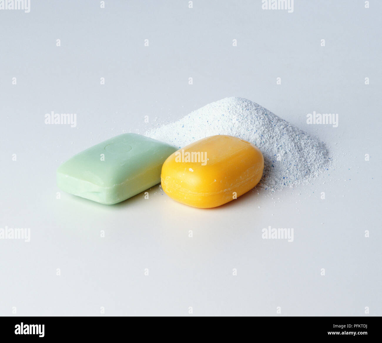 A yellow bar of soap, a green bar of soap and a pile of washing powder ...