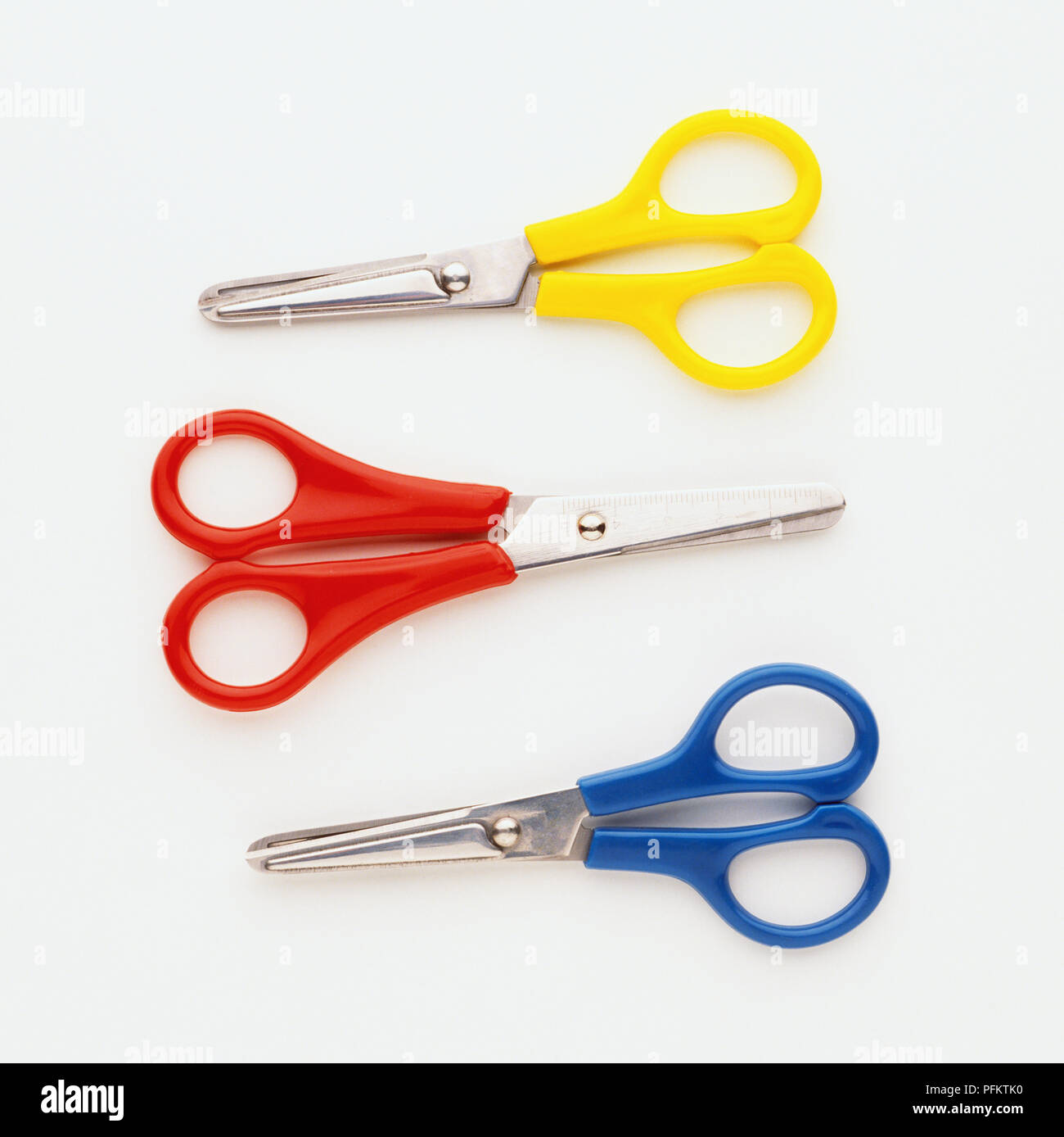 Three pairs of scissors with different coloured handles, yellow, red ...