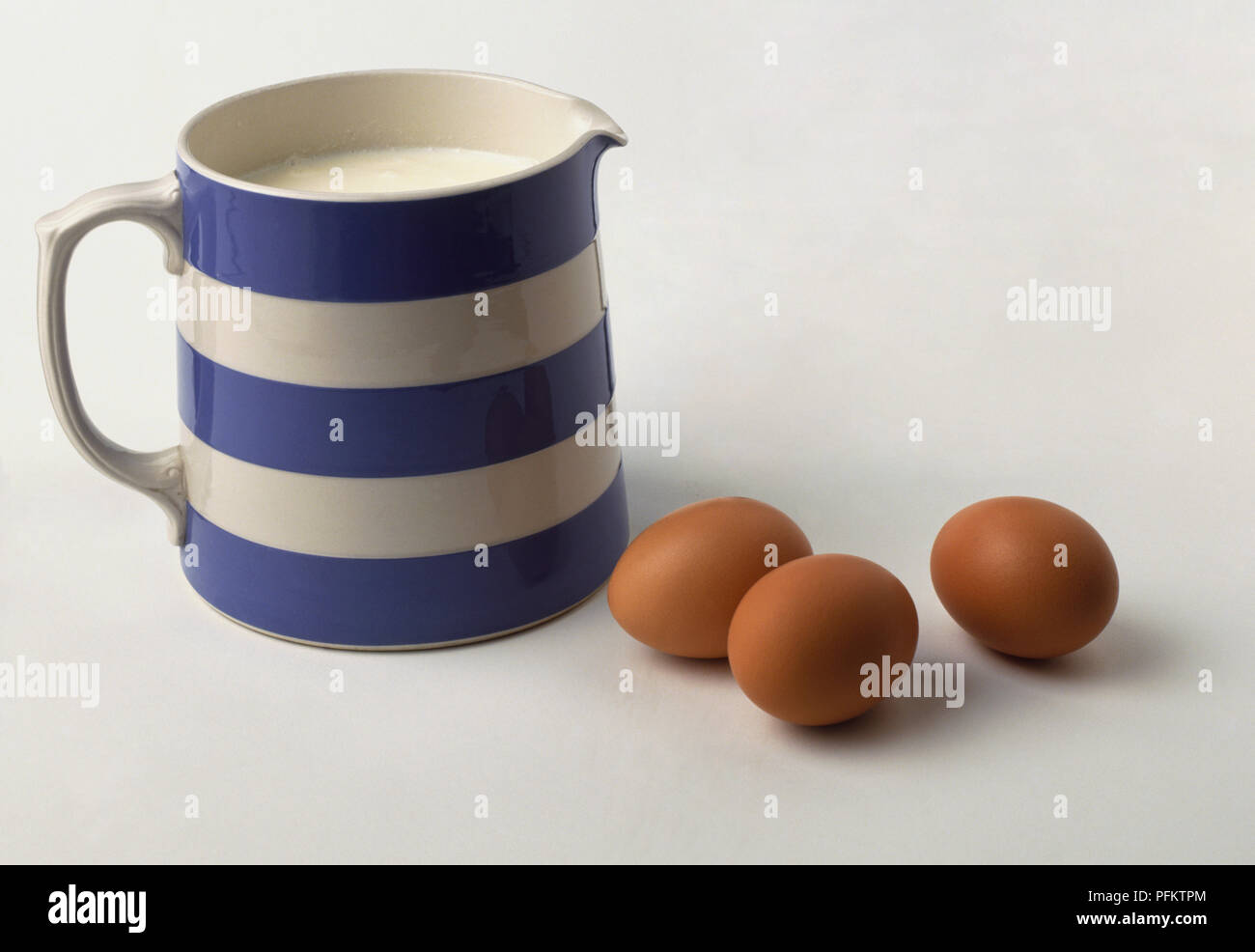 Blue and white jug filled with milk beside three eggs Stock Photo - Alamy