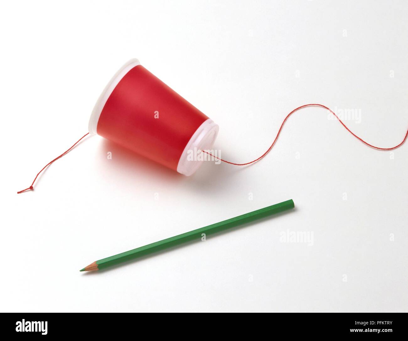 Paper cup with thread running through top and base, and a green pencil ...