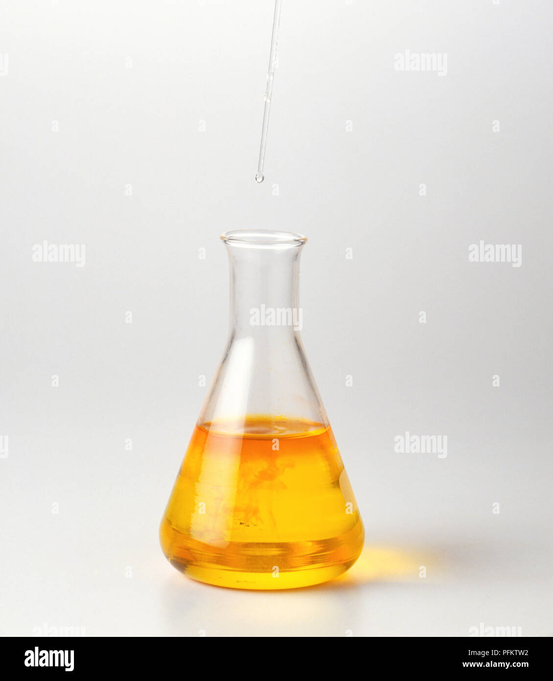 Conical flask containing yellow liquid and pipette held above it Stock ...