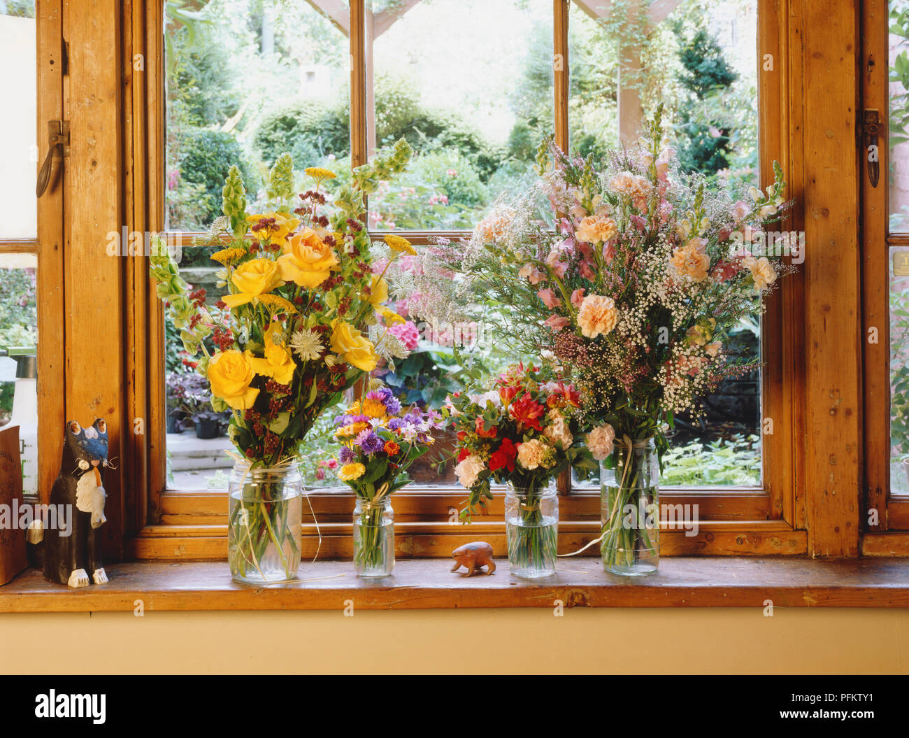 A display of different flowers in vases on a window sill with a view of ...
