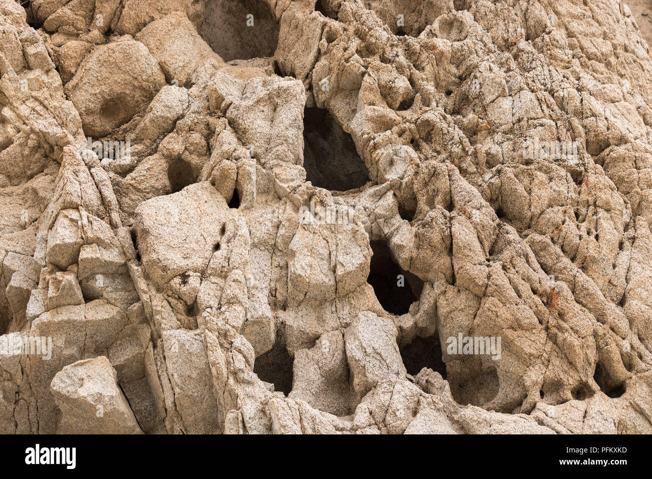 Close up of desert rock wall with deep dark holes and cracks on the ...