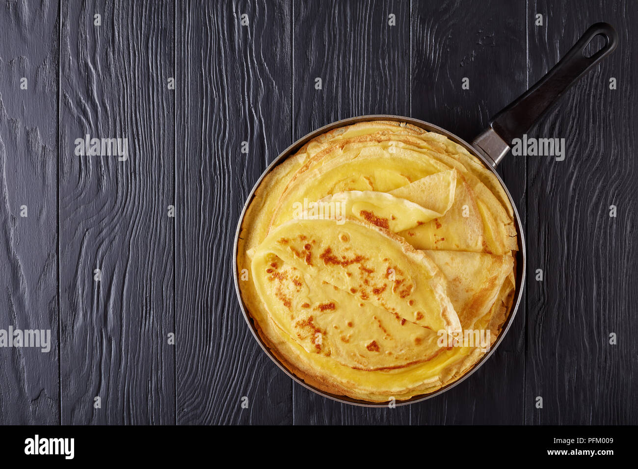 freshly fried french crepes on a skillet on black wooden table, view ...