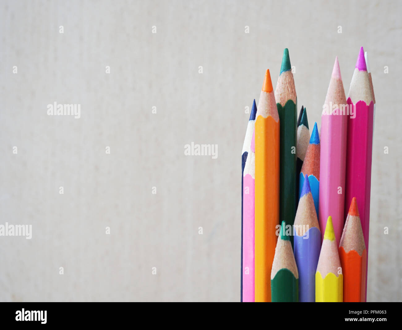 Different colored wooden pencil in bundle on a wooden background with ...