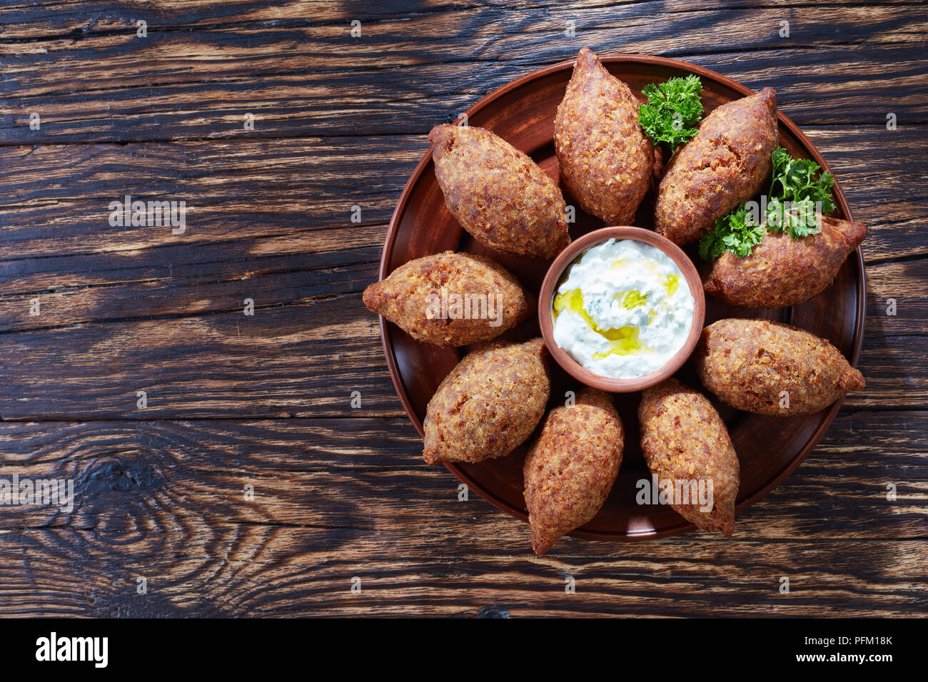 delicious fried kibbeh with yogurt sauce in a bowl served on a clay ...
