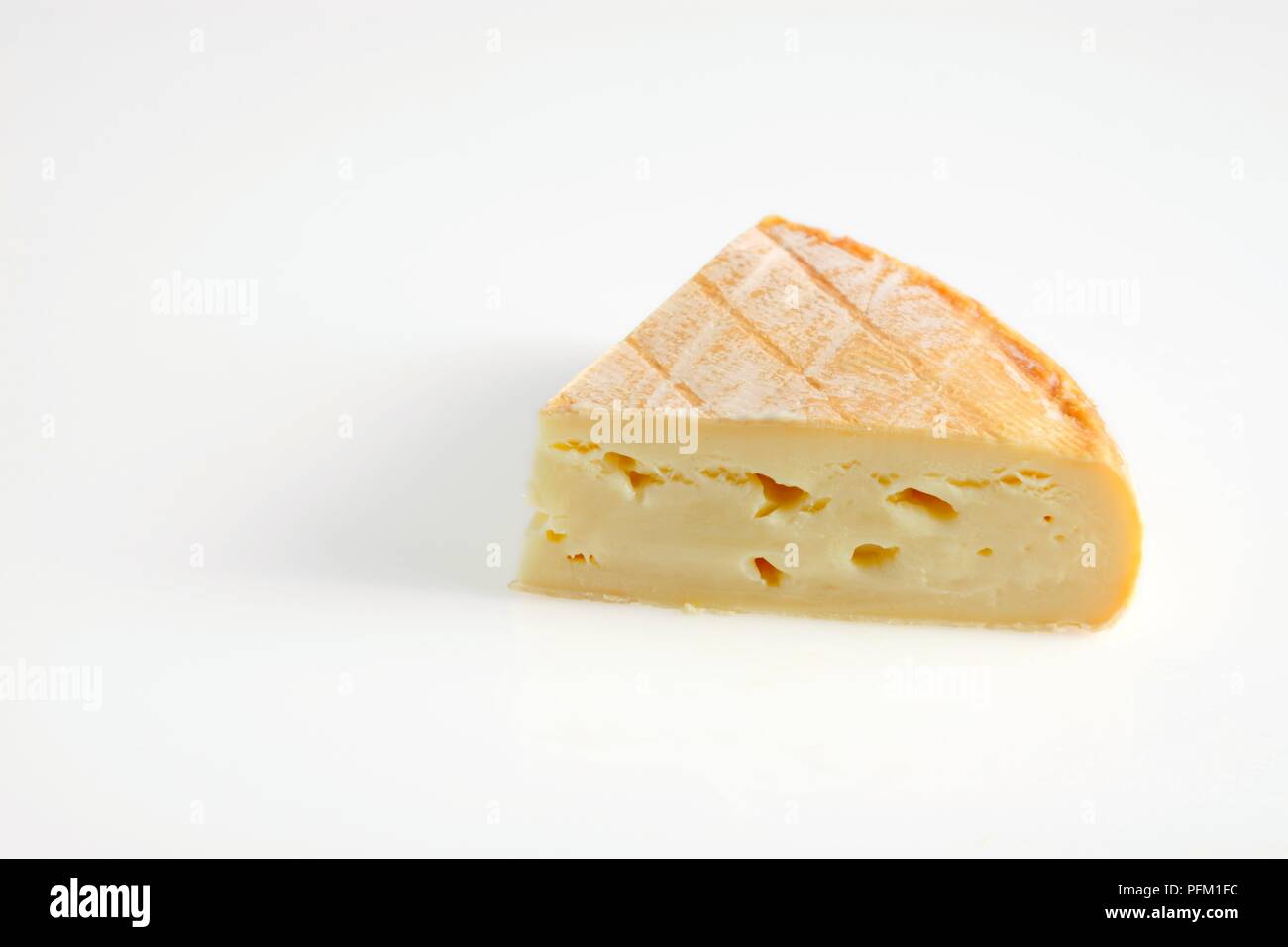 Slice of French Munster AOC cow's milk cheese showing holes Stock Photo ...