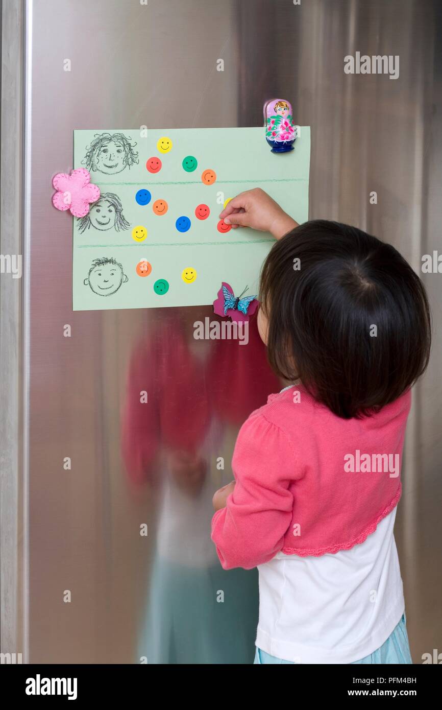 Girl putting smiley-face stickers on chart Stock Photo - Alamy