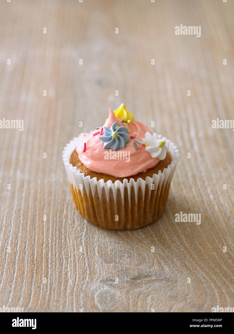 Sponge cup cake with pink icing and icing flowers on top Stock Photo ...